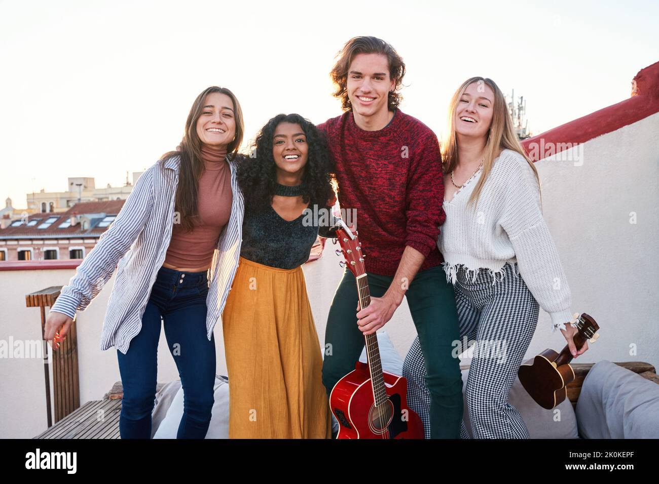 Cheerful young multiracial friends with guitar and ukulele wearing ...