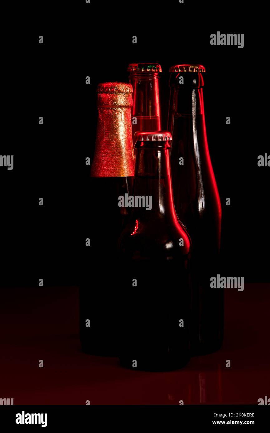 silhouettes of four beer bottles on a black background and lit with red ...