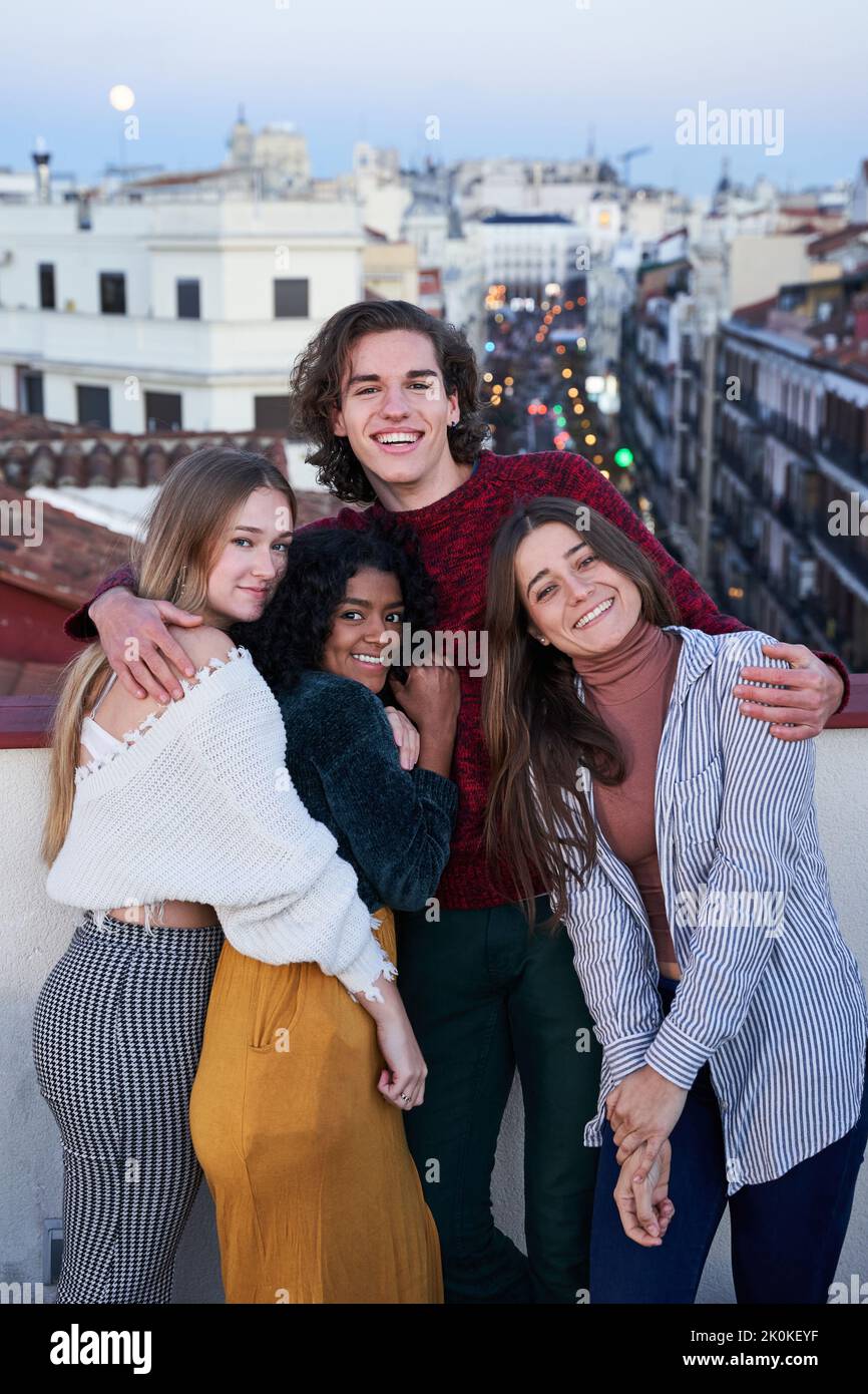 Cheerful young multiethnic friends in casual outfits embracing and ...