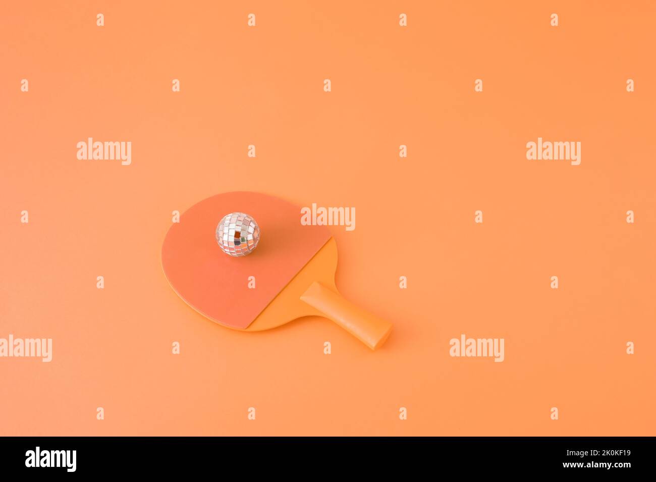 Orange table tennis racket with shiny disco ball Stock Photo - Alamy
