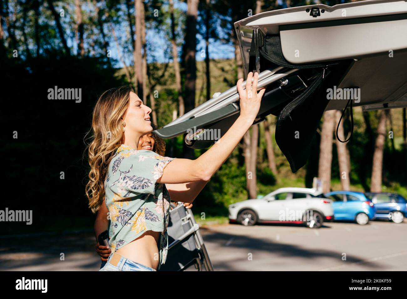 Women closing trunk door of van after taking out a seat in a camping ...