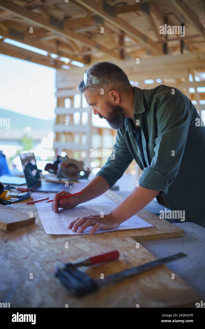 Construction worker smiling, drawing and checking blueprints, diy eco ...