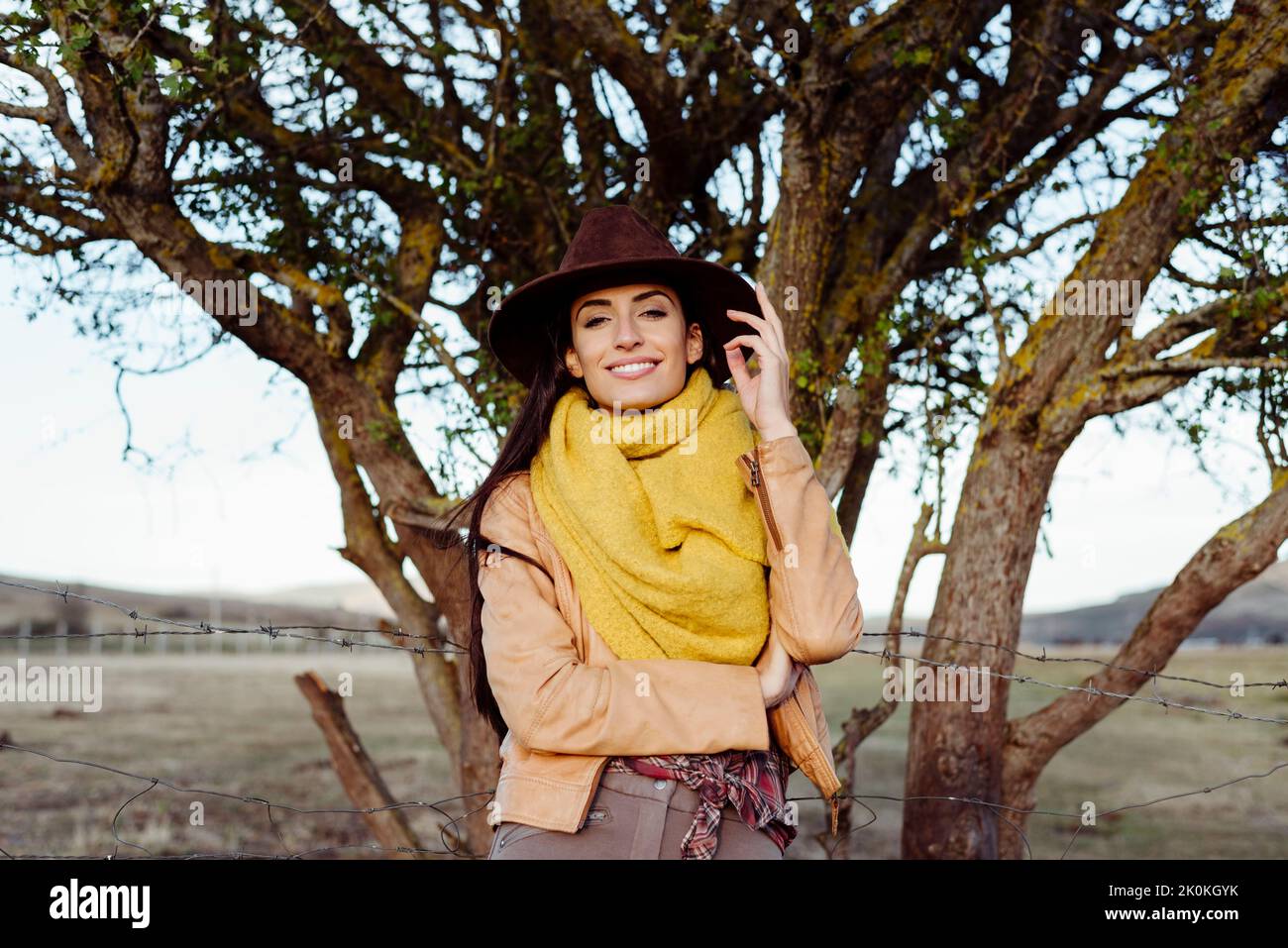 Beautiful trendy brunette in colorful scarf and brown cowboy hat ...