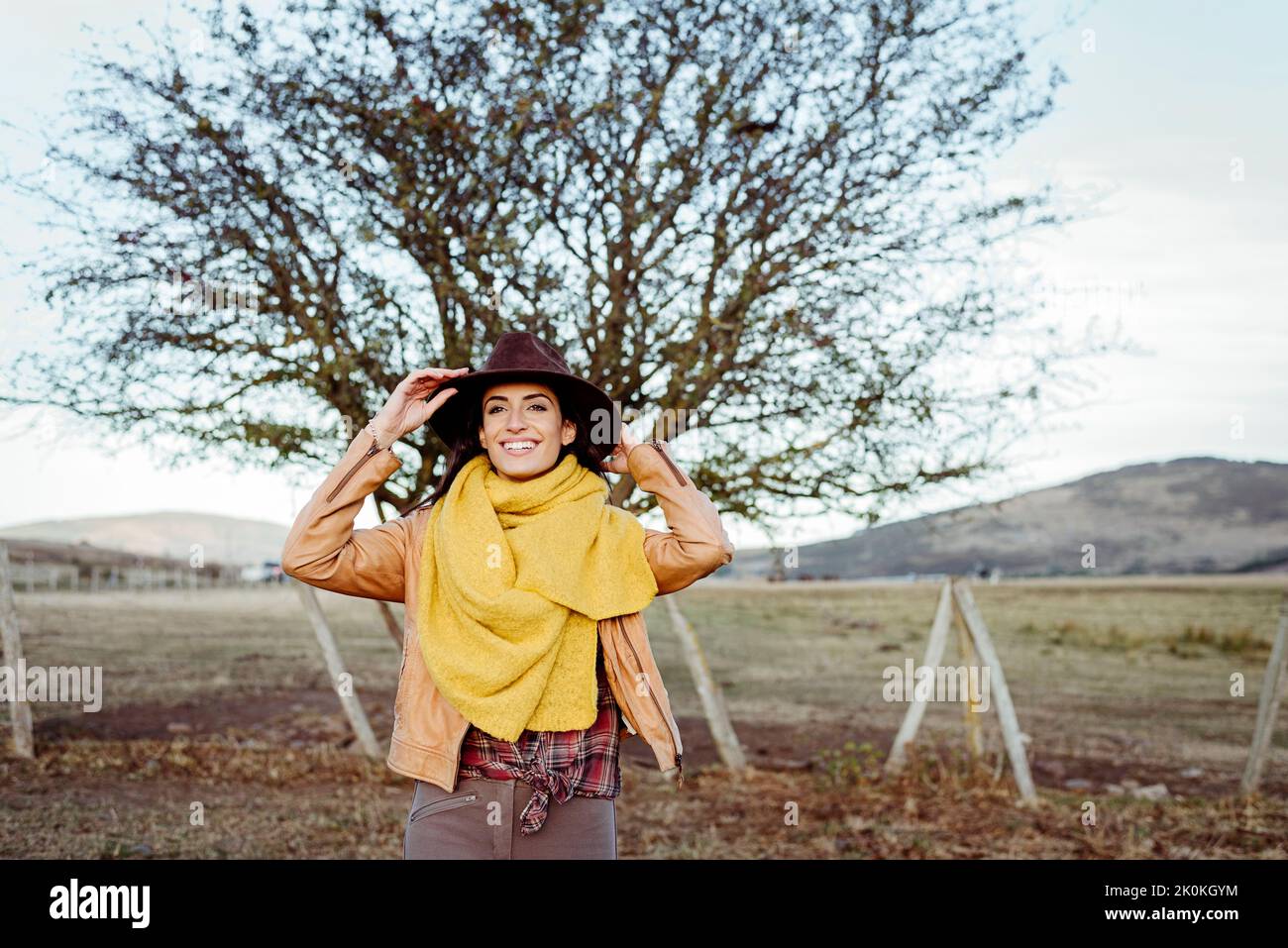 Beautiful trendy brunette in colorful scarf and brown cowboy hat ...