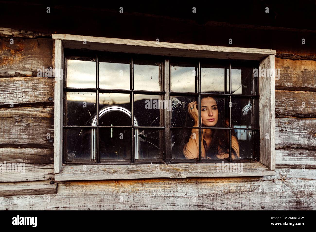 Shot through window of old wooden ranch house with woman looking ...
