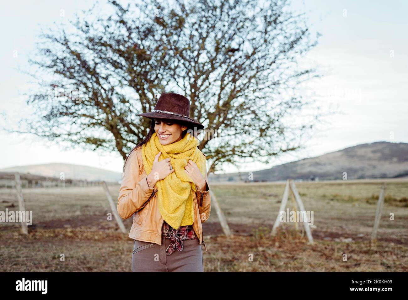 Beautiful trendy brunette in colorful scarf and brown cowboy hat ...