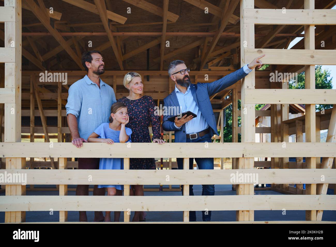 Sales agent showing plans of new house to young family on construction ...