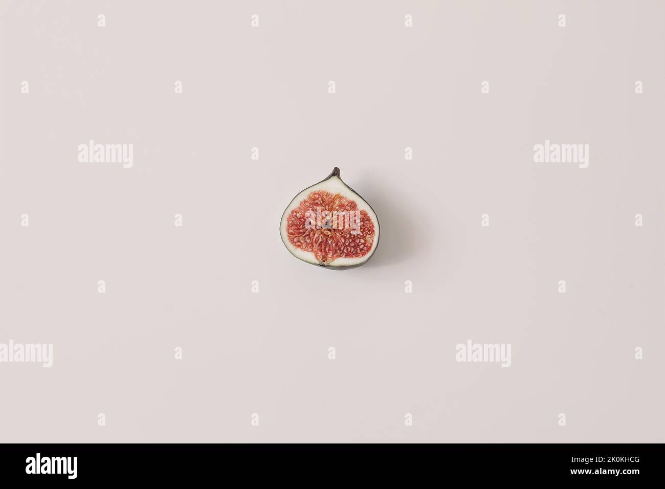 Fresh cut juicy purple fig with red seeds isolated on pink pastel ...