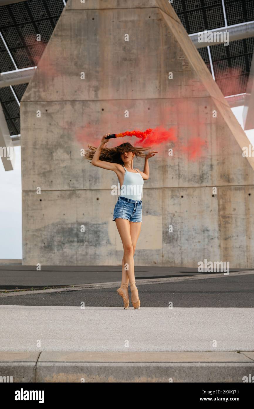 Woman holding colorful smoke bomb dancing ballet outdoors Stock Photo ...