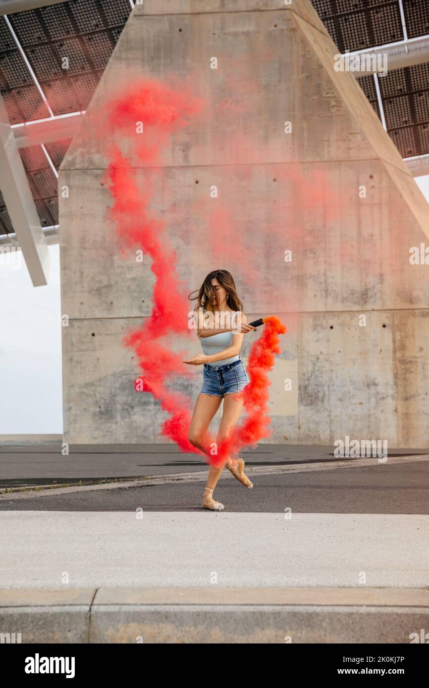 Woman holding colorful smoke bomb dancing ballet outdoors Stock Photo ...