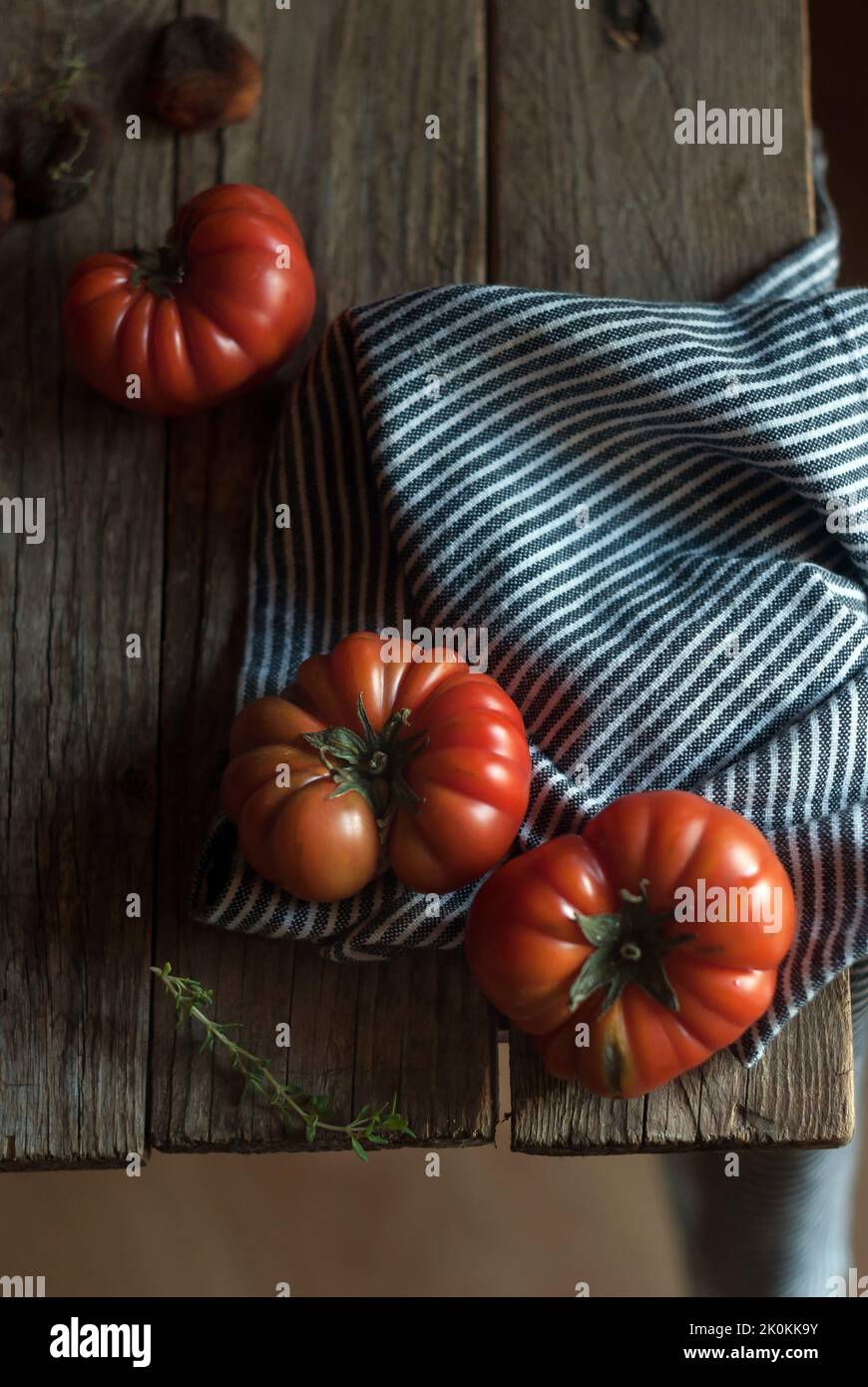 From above of ripe red tomatoes with striped napkin on wooden table ...
