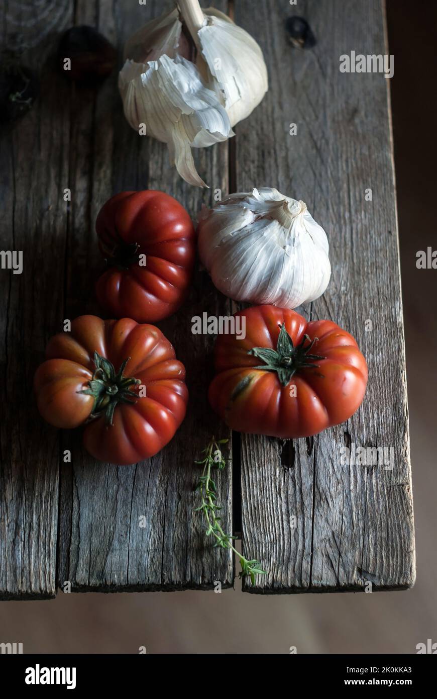 From above of ripe red tomatoes with white garlic bulbs composed on ...