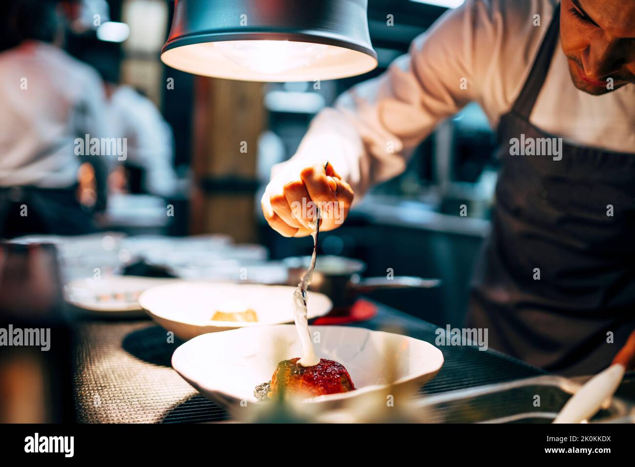 Crop professional chef pouring white sauce on dish in elegant plate ...