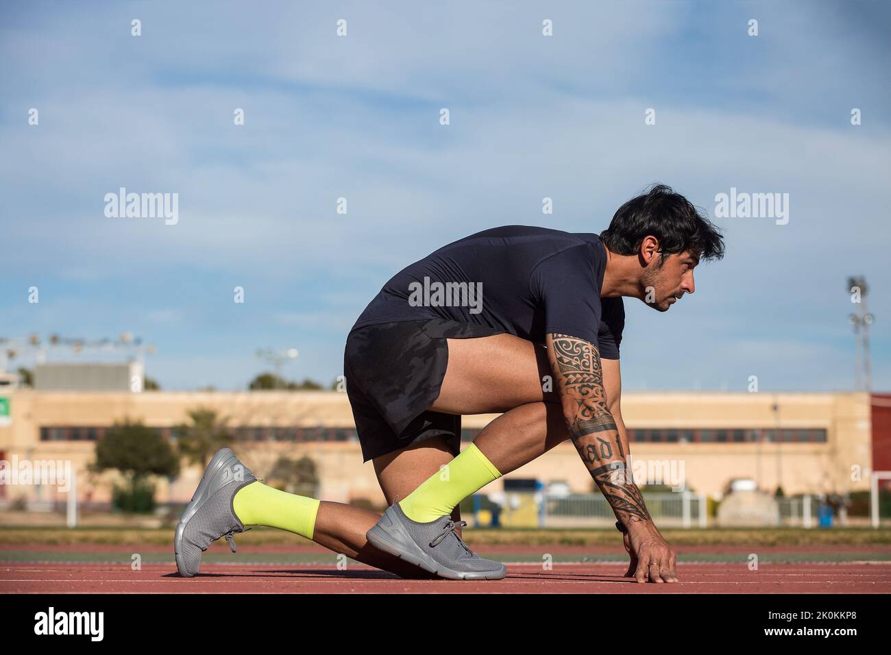Side view of Hispanic male professional runner standing in crouch start ...