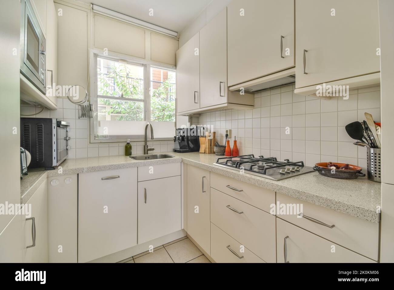 Interior of light kitchen with modern cupboards and appliances located ...