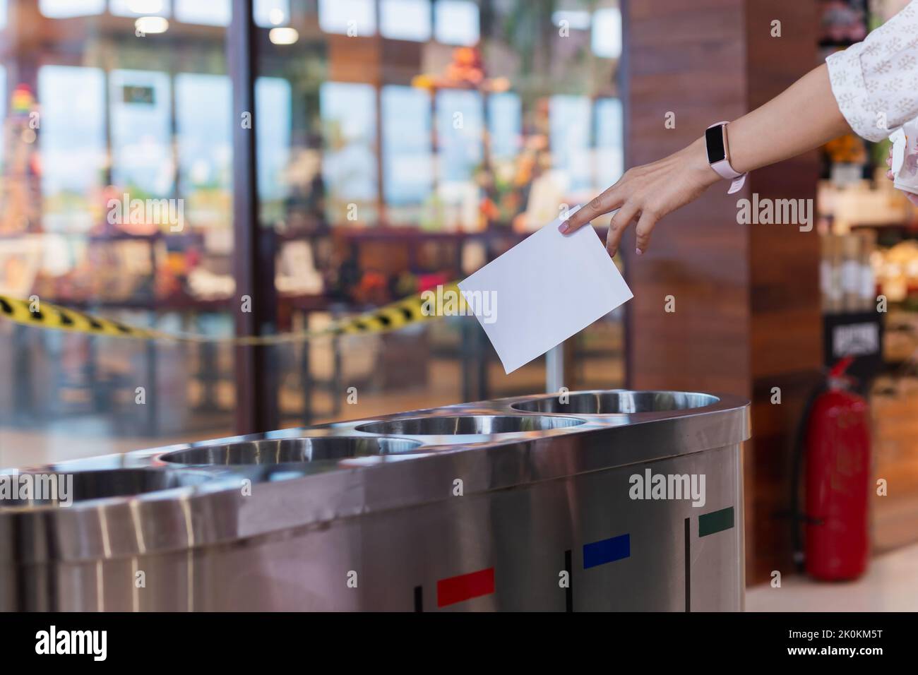Woman putting paper into trash bin in shopping mall Stock Photo - Alamy