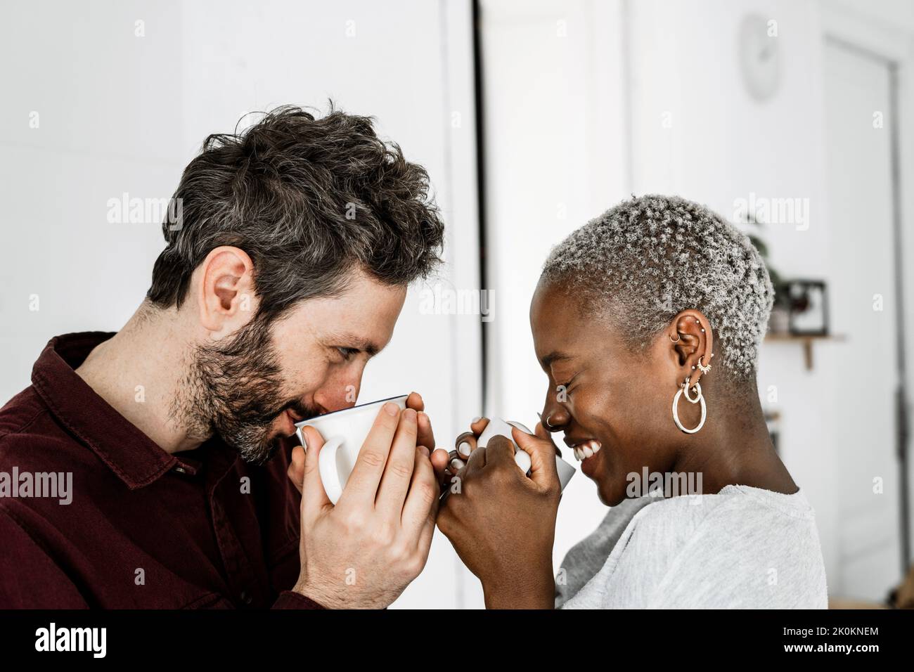 Side view of positive multiethnic couple laughing while standing close ...