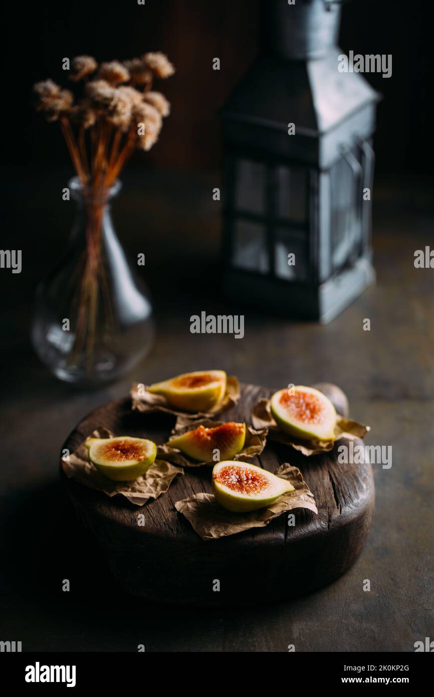 Top view of fresh sweet figs arranged on wooden chopping board on dark ...