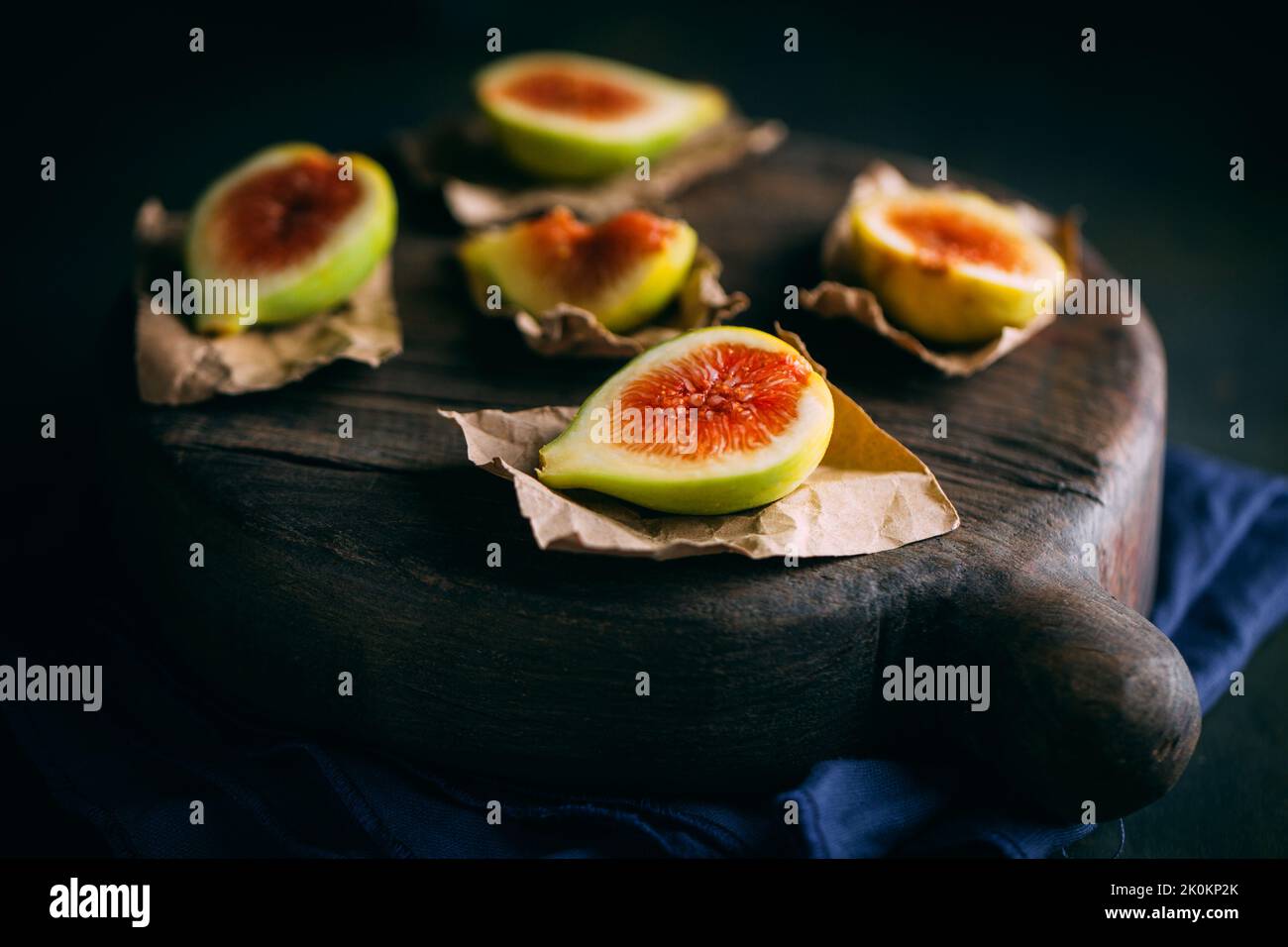 Fresh sweet figs arranged on wooden chopping board on dark background ...