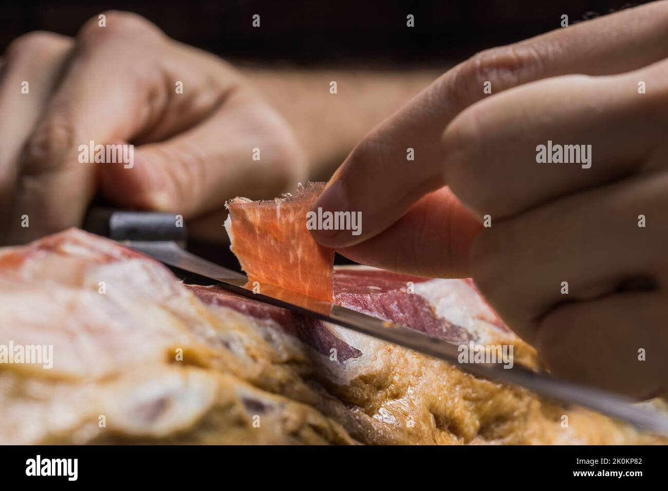 Crop unrecognizable cook cutting slice of tasty dry cured Spanish jamon ...
