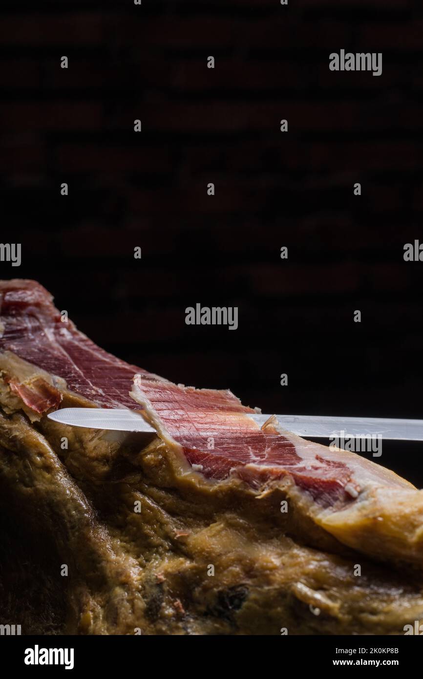Crop unrecognizable cook cutting slice of tasty dry cured Spanish jamon ...