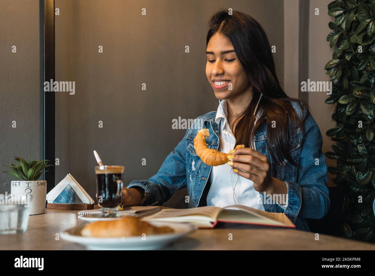 Content smart young Hispanic female student writing in copybook while ...