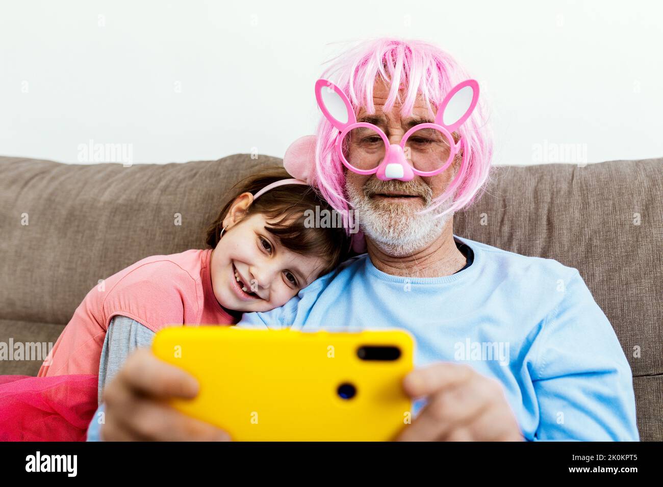 Happy child sitting on couch with grandfather in big pink plastic ...