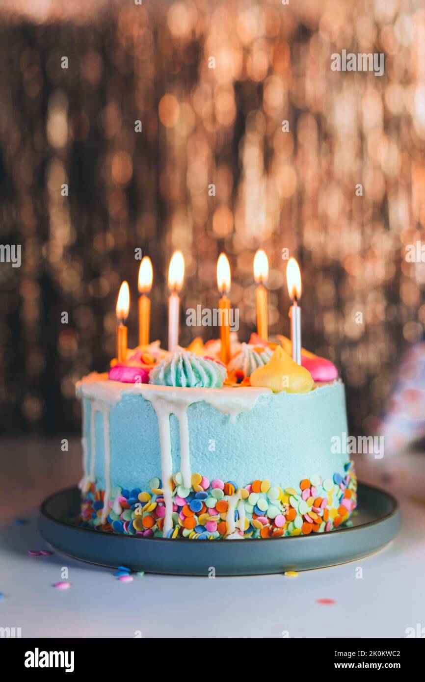 Colorful birthday cake with sprinkles and burning candles on the ...