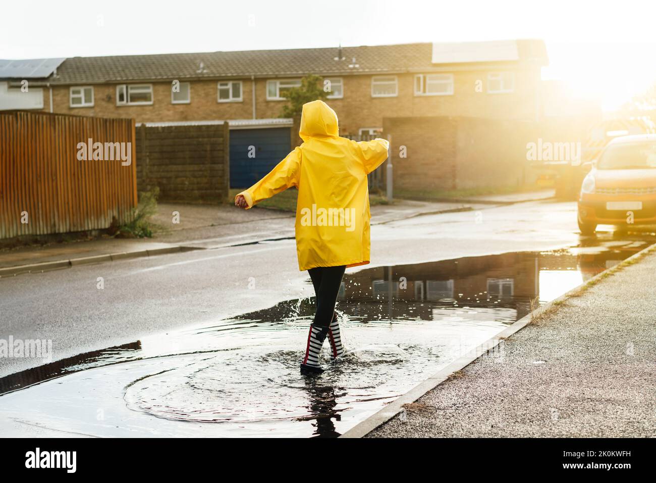 Woman having fun on the street after the rain. Back view woman wearing ...