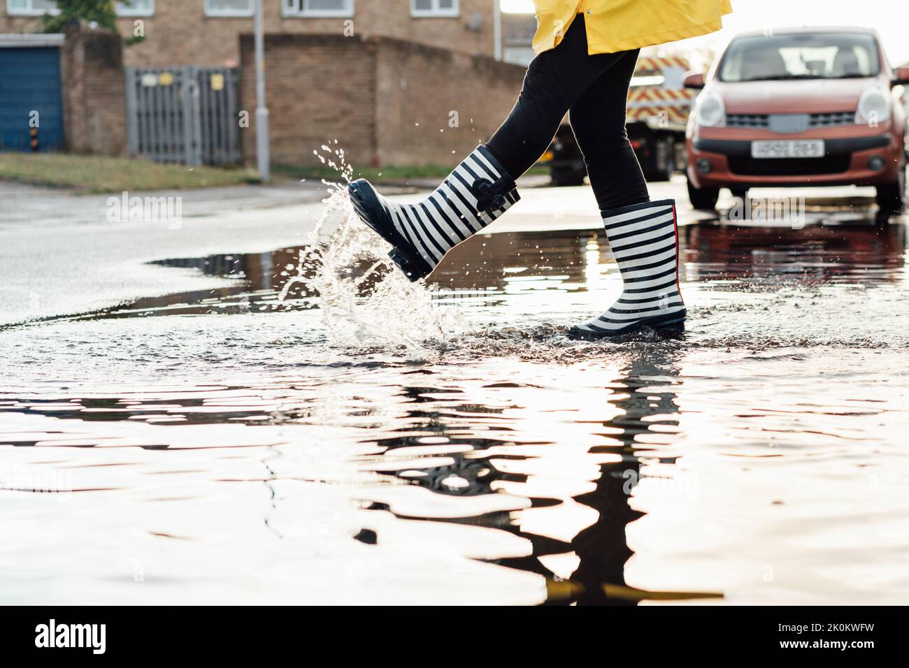 Woman having fun on the street after the rain. Close up female legs in ...