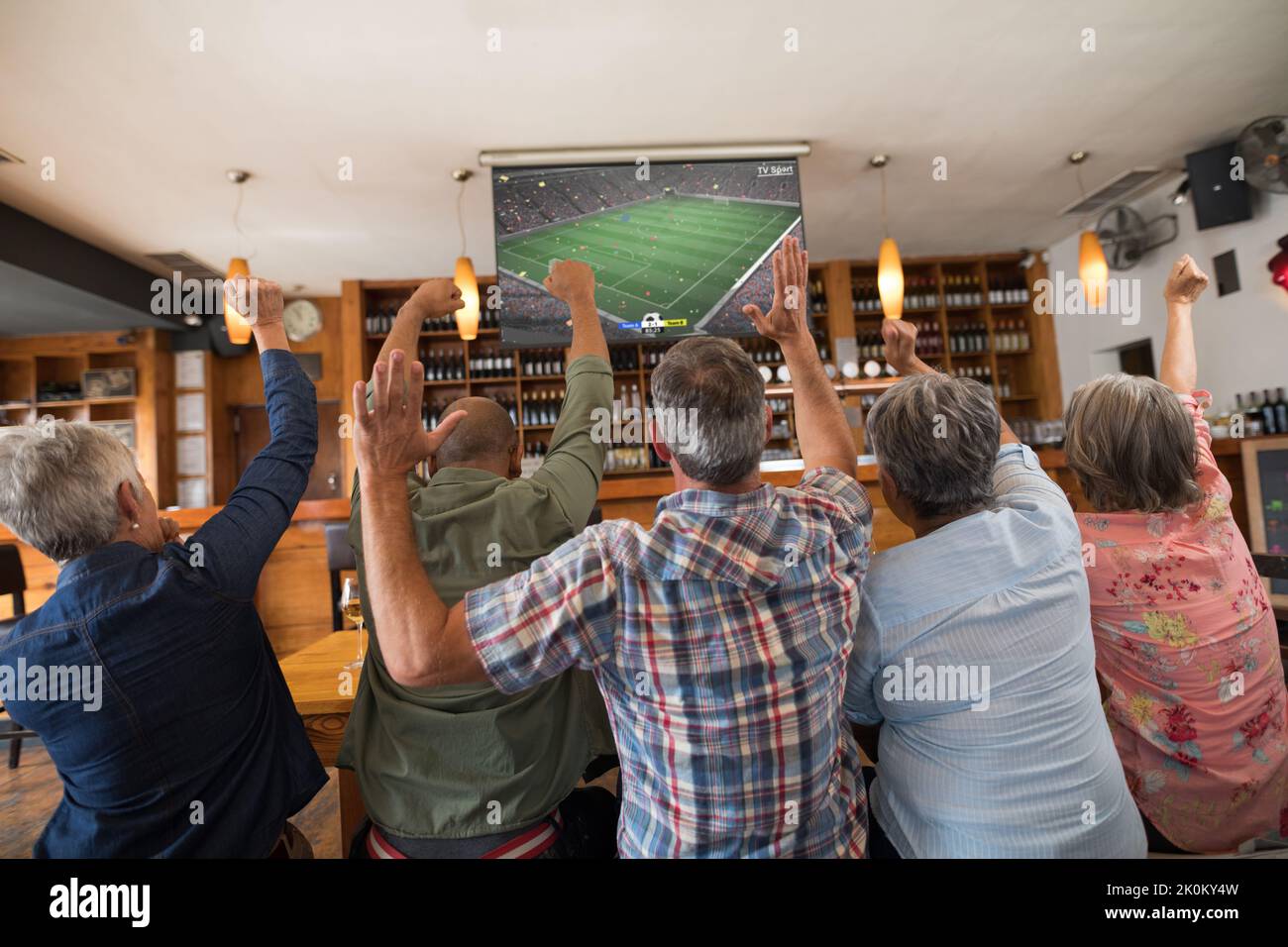 Group of senior diverse friends sitting in the bar and watching ...