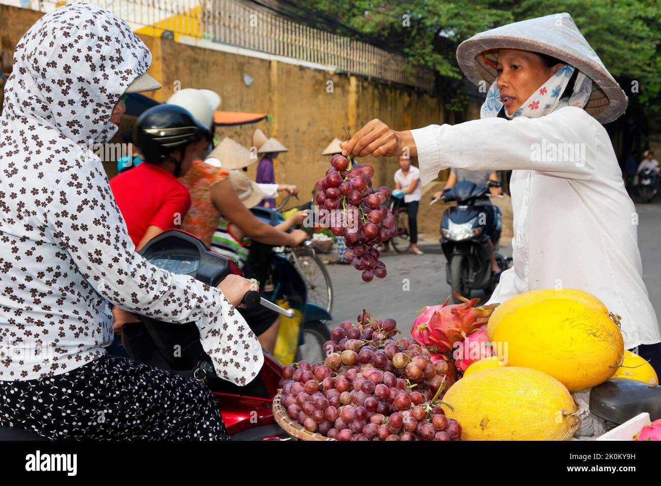 Vietnamese vendor wearing bamboo hat working in open air street market ...