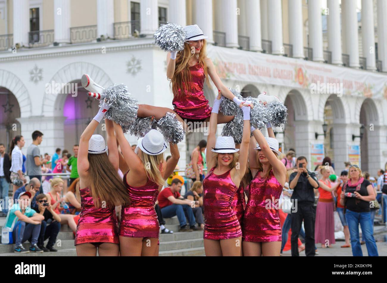 Girls cheerleaders in red costumes and white hats performing acrobatics ...