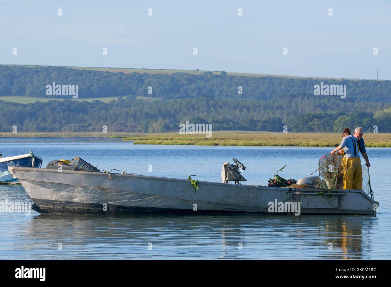 Two people checking fishing nets in an open boat in Poole Harbour ...