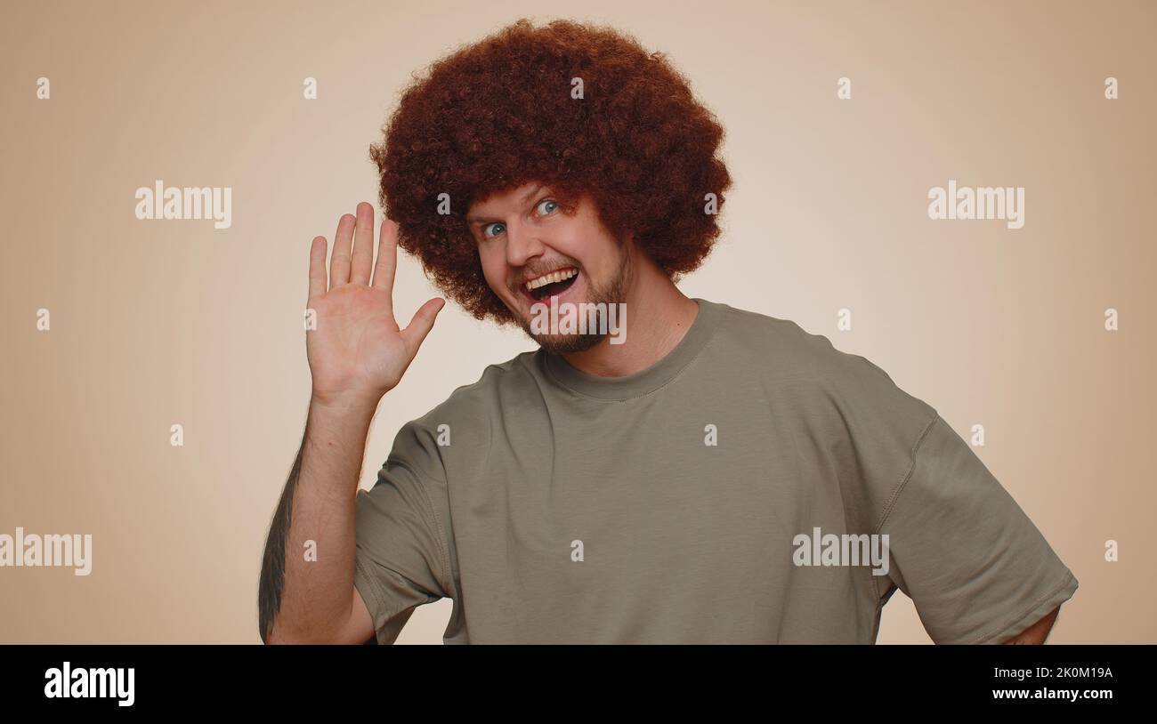 Handsome bearded man in t-shirt smiling friendly at camera and waving ...