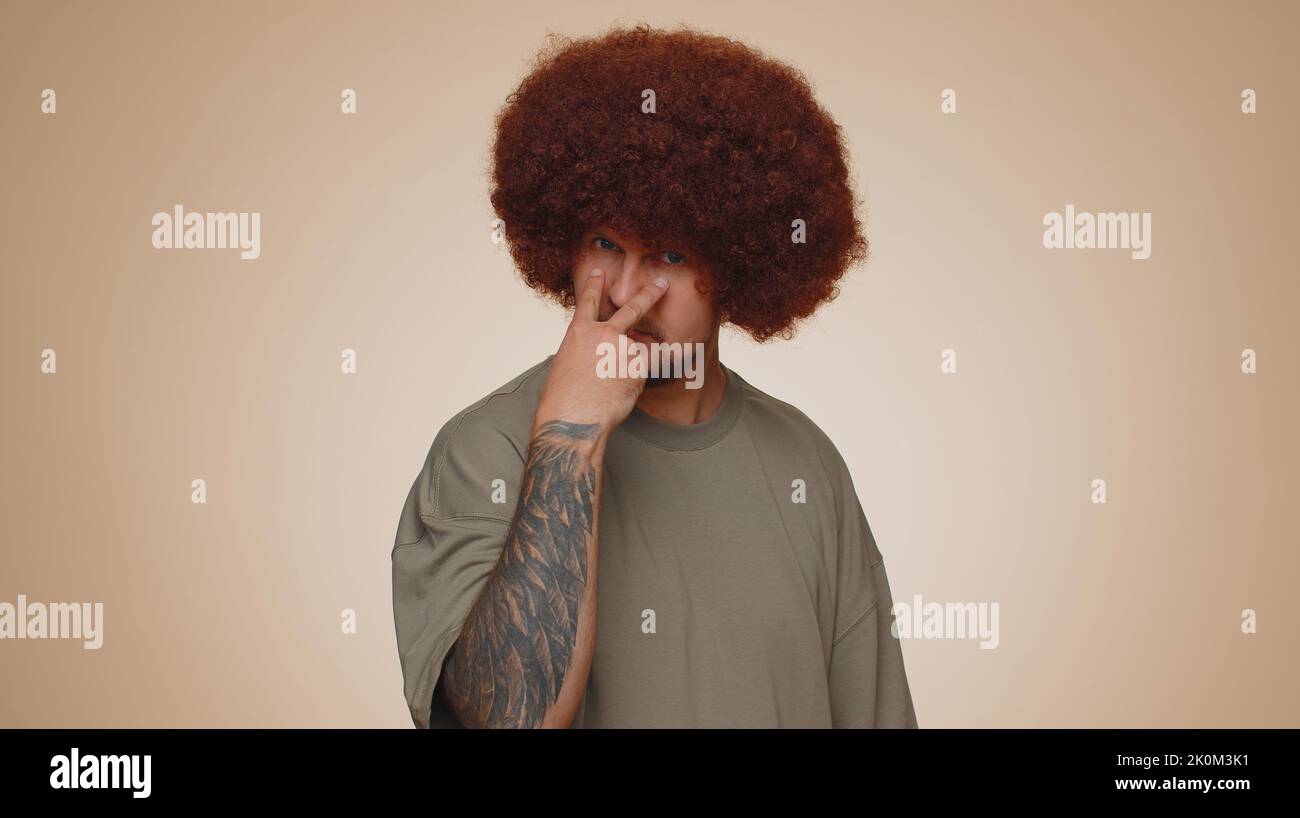 I am watching you. Man with lush hairstyle wig pointing at his eyes and ...