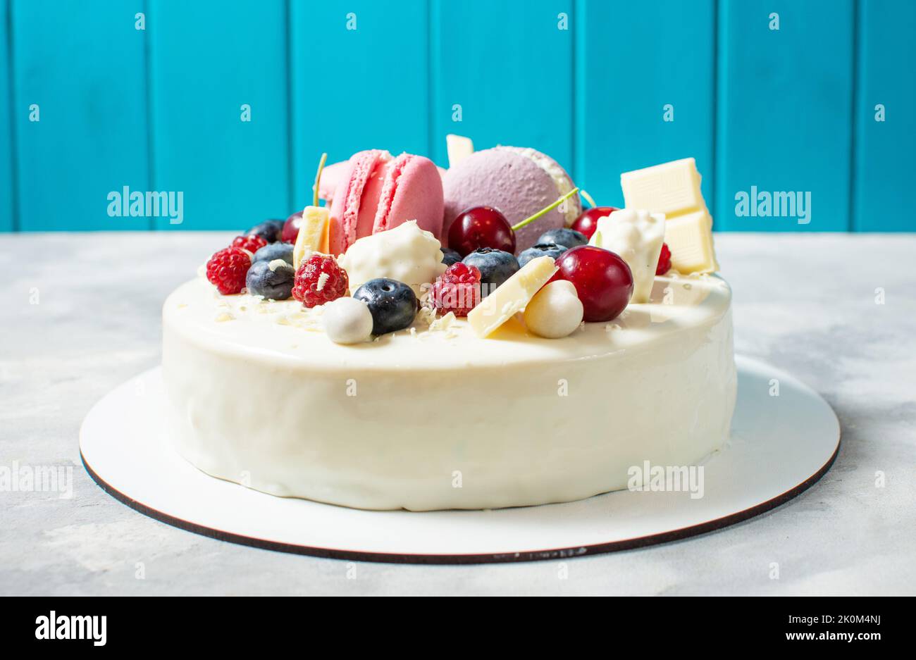 Tender white cake decorated with melted white chocolate, macaroons ...