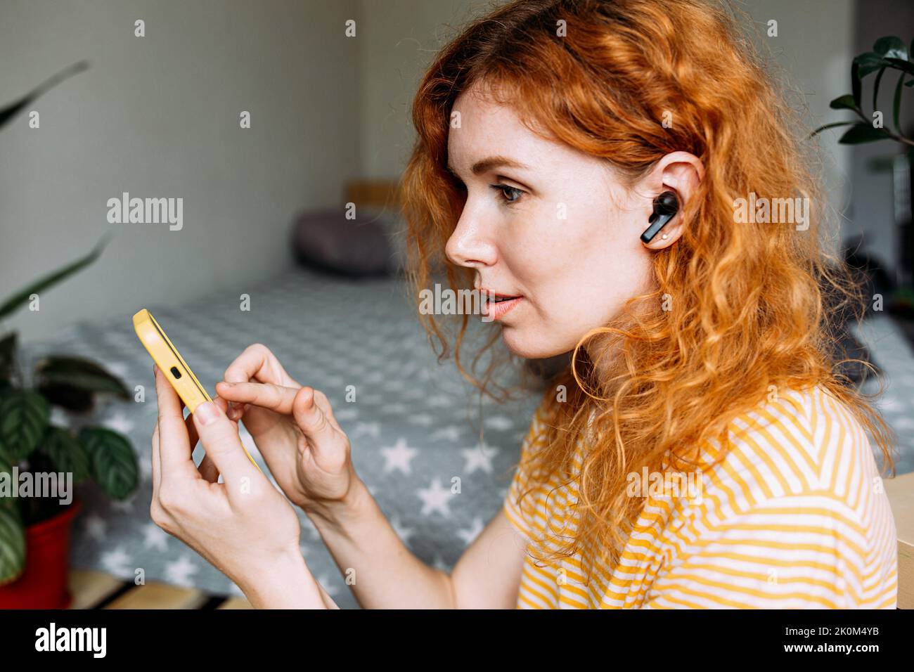 Happy red-haired girl listening music, at home in wireless headphones ...