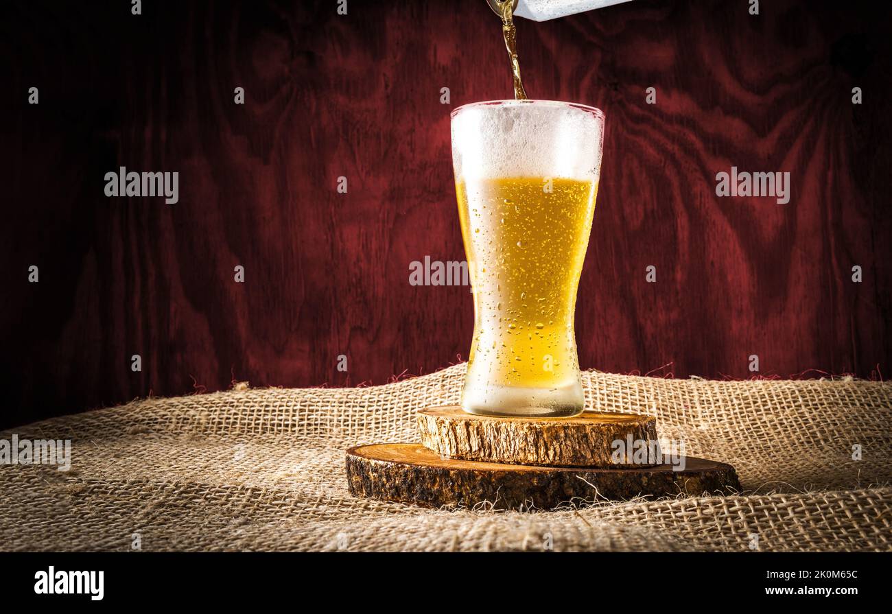 Beer falling from a can to a glass on a red rustic background on a ...