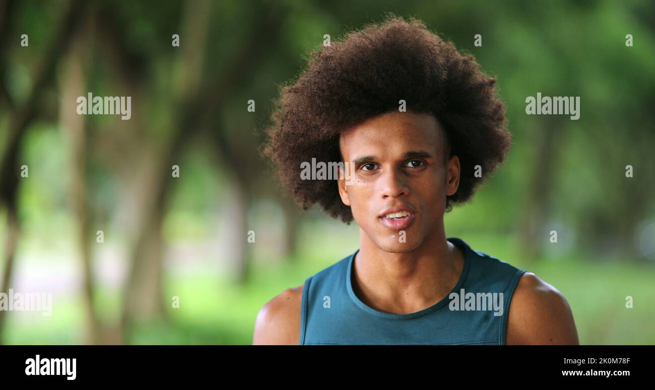 Happy confident young black african man walking forward at park feeling ...