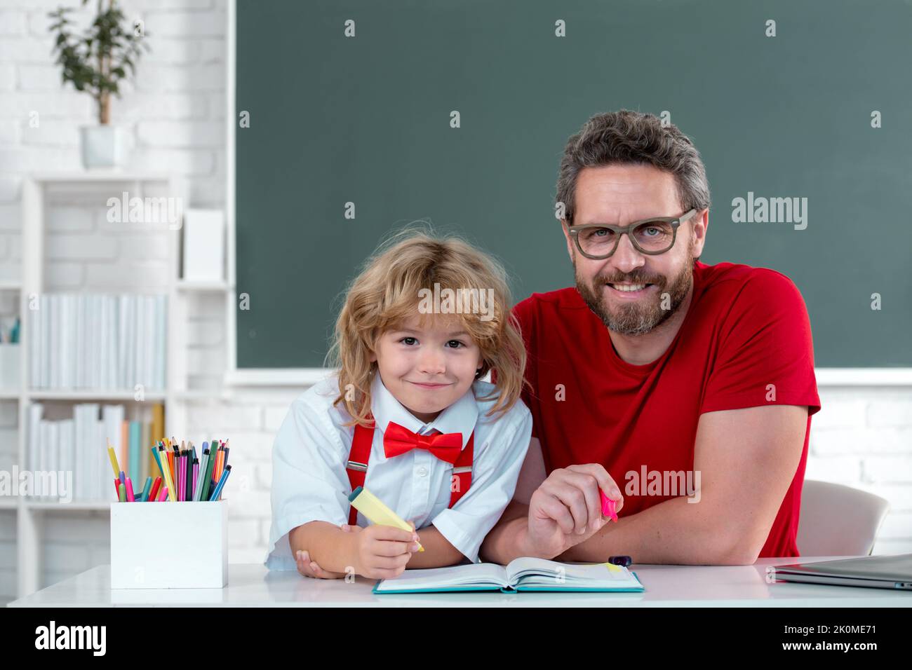 School pupil with teacher in classroom. Teacher and little student ...