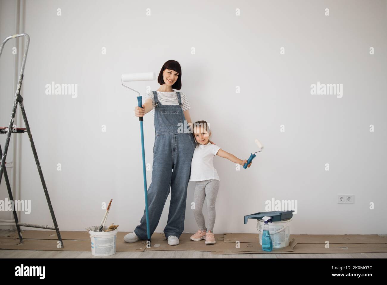 Young mother and a funny child girl have fun during the repair holding ...