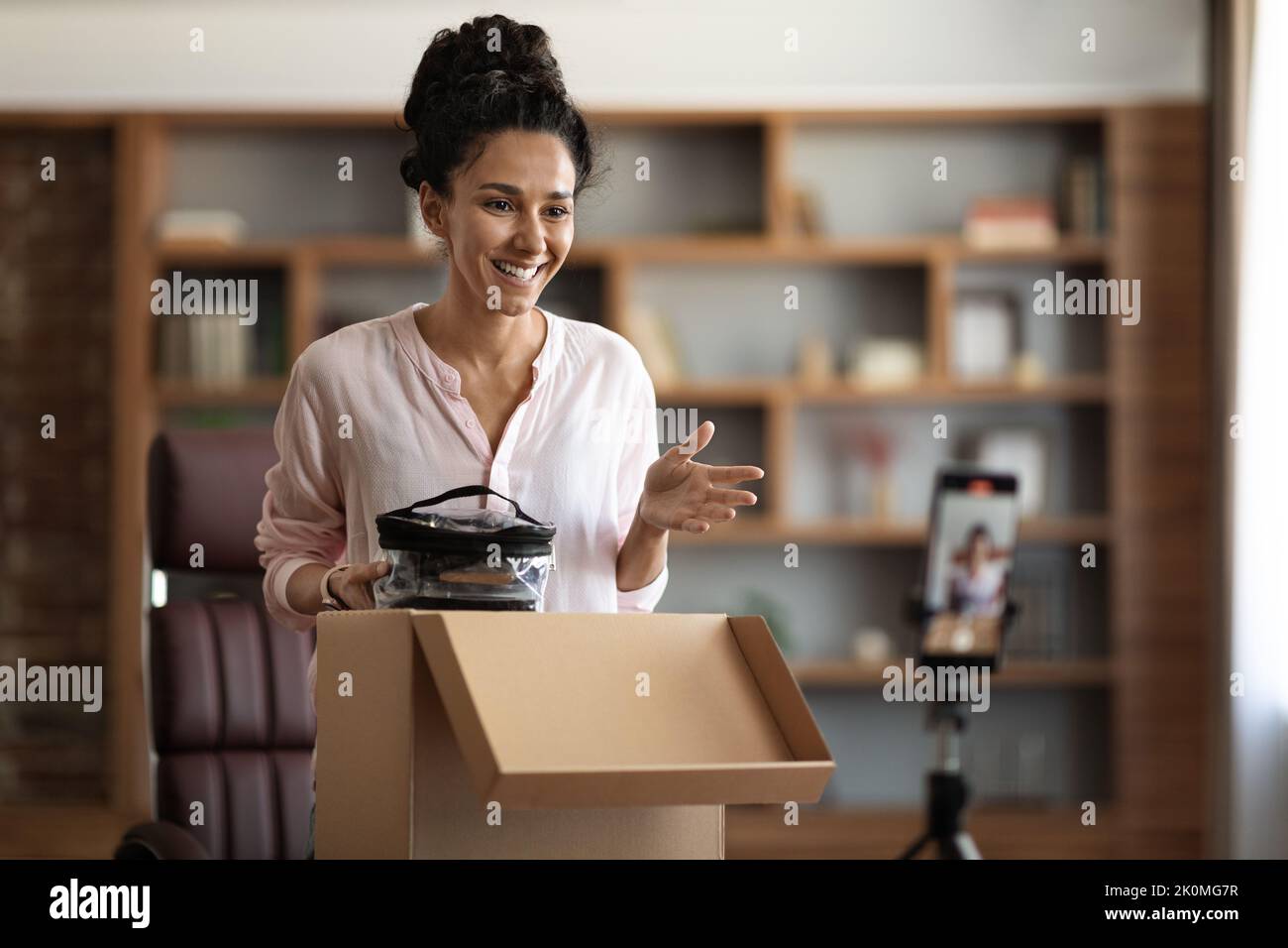 Cheerful young woman unpacking delivery box and recording video Stock ...