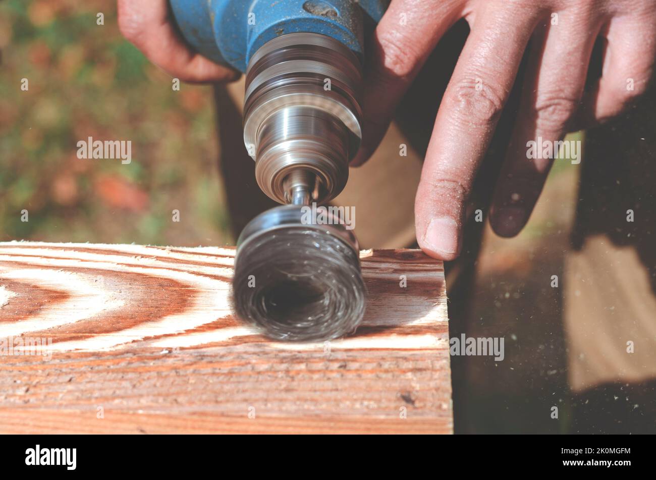 Wire brush for wood working, on a drill. Male hand is holding brushing ...