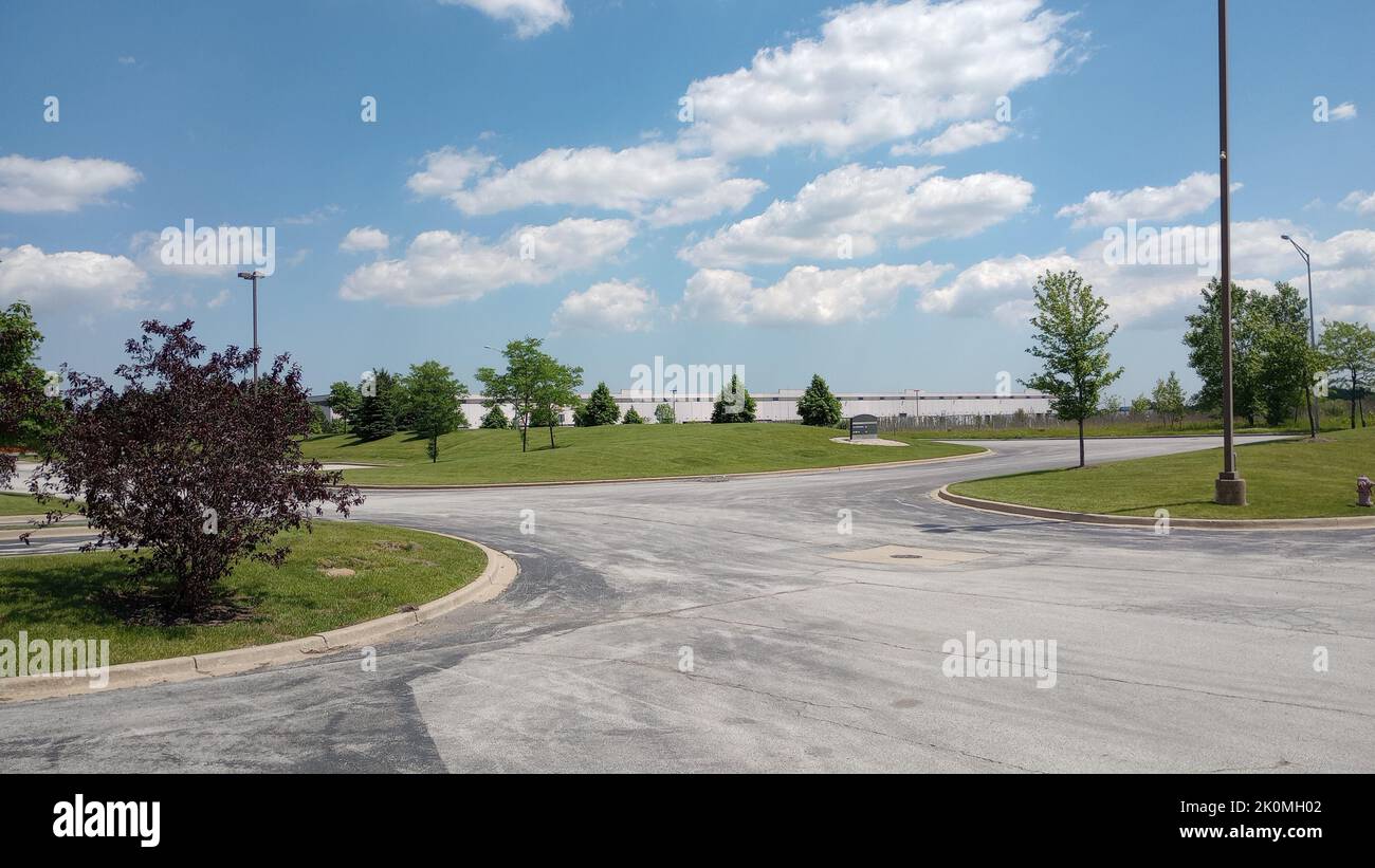A curve street with trees in the middle and a cloudy blue sky Stock ...