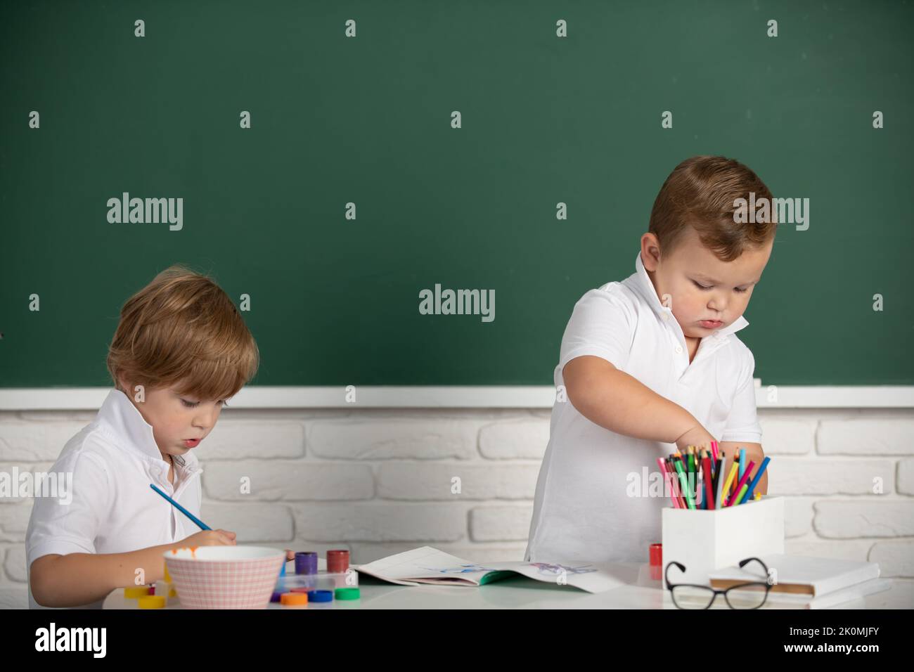 Portrait school kids bosy doing art homework, holding pencil, writing ...