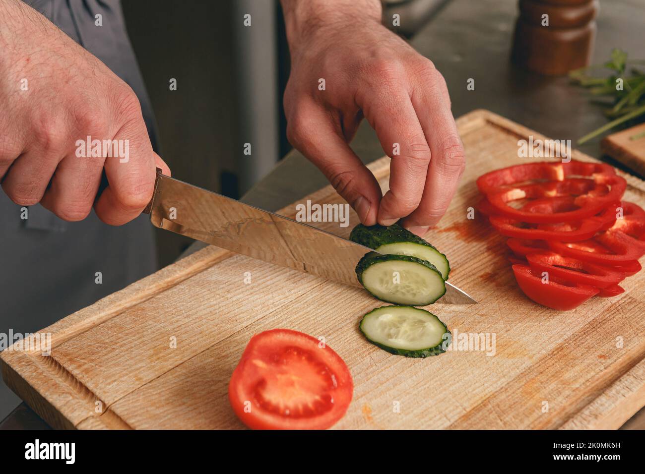 Busy chef cutting tomatoes and cucumbers on a board in modern ...