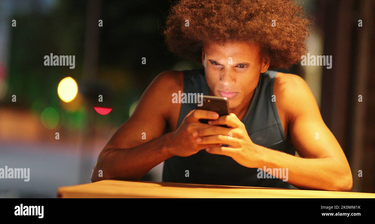 Upset african man looking at cellphone with surprise and disbelief ...