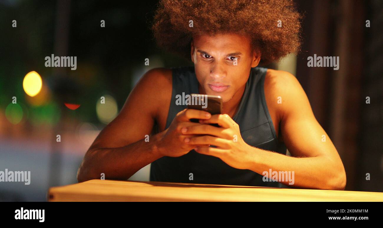 Upset african man looking at cellphone with surprise and disbelief ...