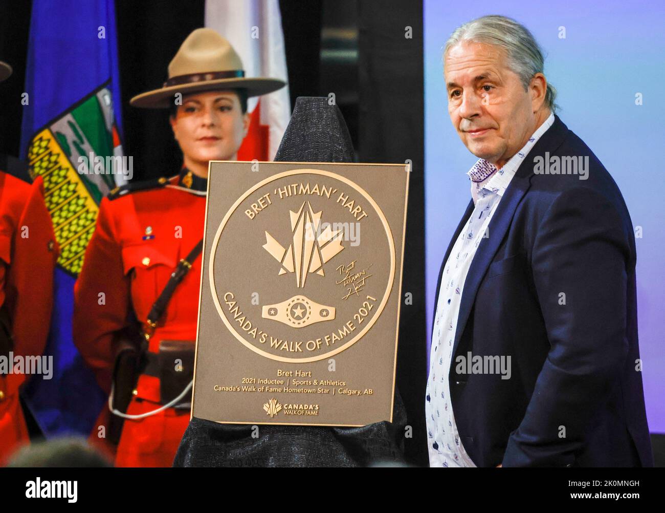 Former WWE wrestler Bret Hart stands with a replica plaque representing ...